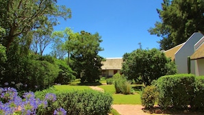 Um jardim bem cuidado com um caminho que leva a um edifício com telhado de palha.