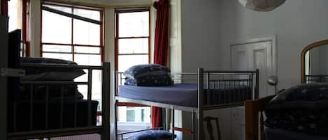 Quarto com beliche, janela, porta e espelho na parede.
