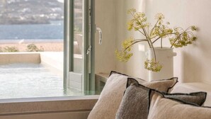Quarto com vista para o mar, porta de vidro e um vaso de flores sobre uma mesa.