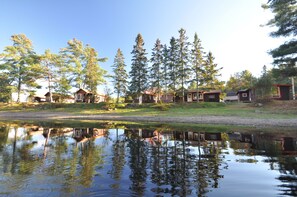 Um terreno à beira do lago com cabanas e reflexo na água.