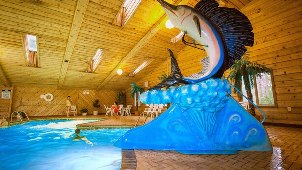 Piscina interna com uma grande escultura decorativa de um peixe e uma sereia.