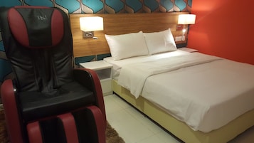 Quarto de hotel com uma cama, uma cadeira, duas luminárias de cabeceira e uma mesinha de cabeceira.