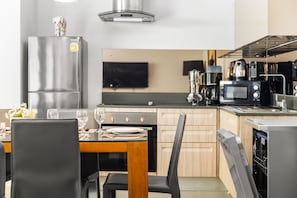 Cozinha moderna com geladeira de aço inoxidável, mesa de jantar de madeira e lava-louças.