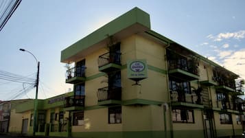 Um edifício de vários andares com varandas, um letreiro com 'La Guaria Inn & Suites' e um poste de luz em primeiro plano.