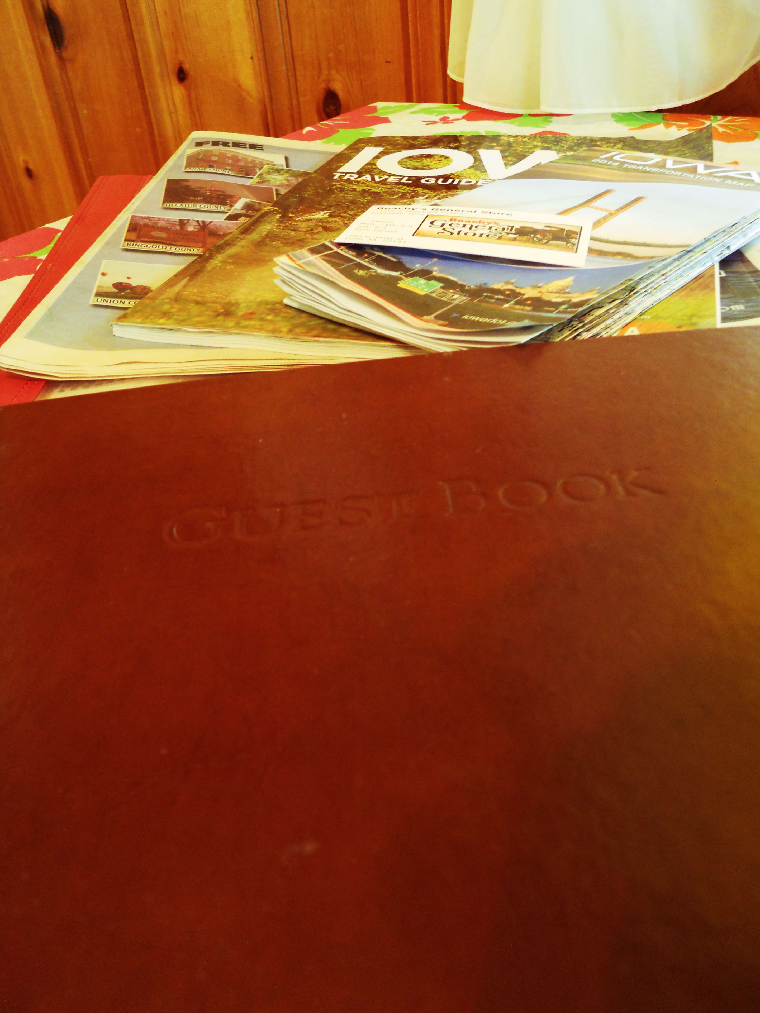 Uma mesa com uma pilha de guias de viagem e um livro encadernado em couro intitulado "Glacier Book".