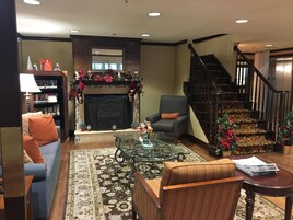 Uma sala de estar com lareira, escada, sofá, mesa de centro e estante de livros.