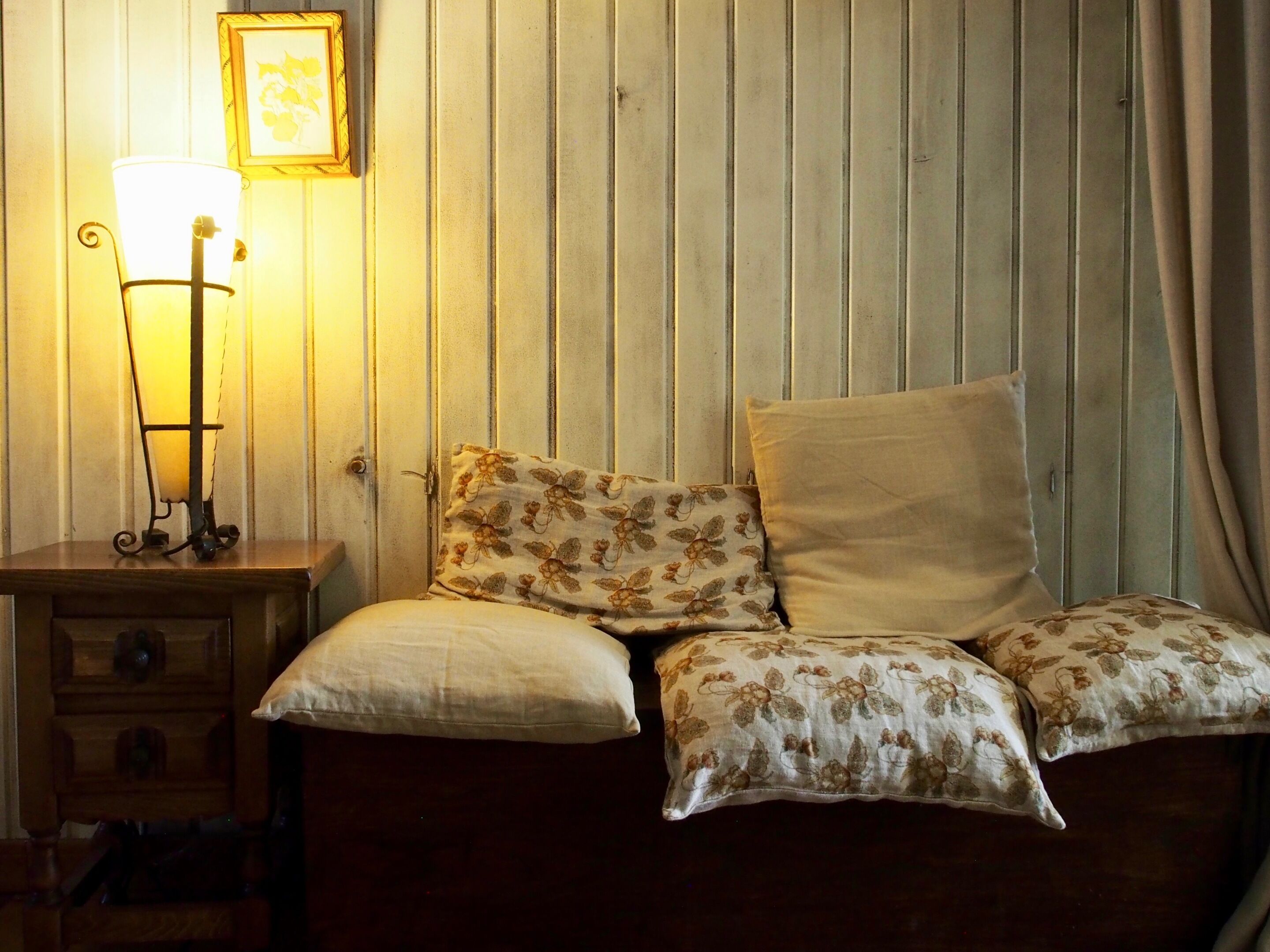 Uma cama com almofadas estampadas e uma mesa de cabeceira com abajur.
