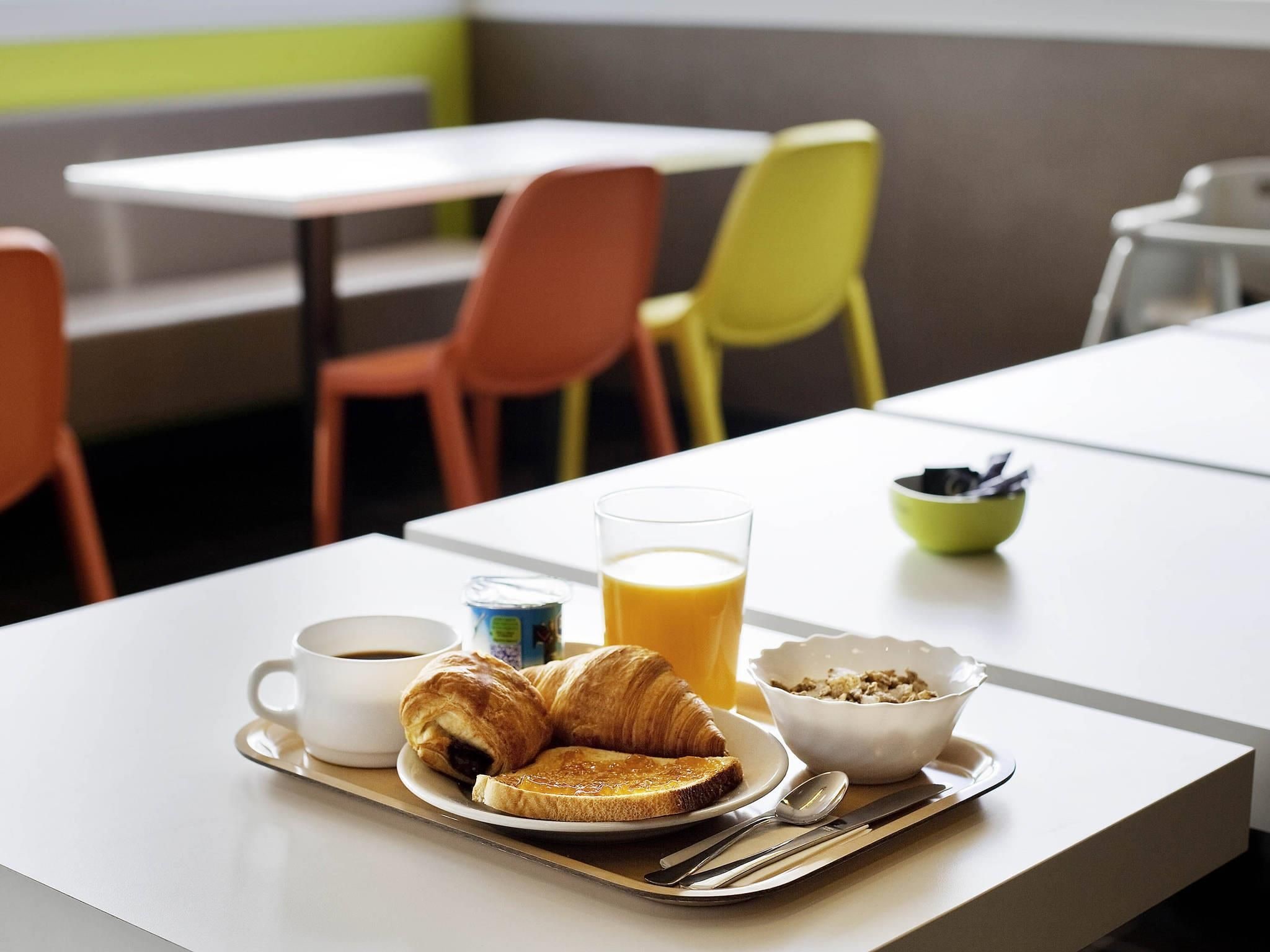 Disposição para o café da manhã com croissants, um copo de suco de laranja, uma tigela de cereal e uma xícara de café sobre uma mesa.