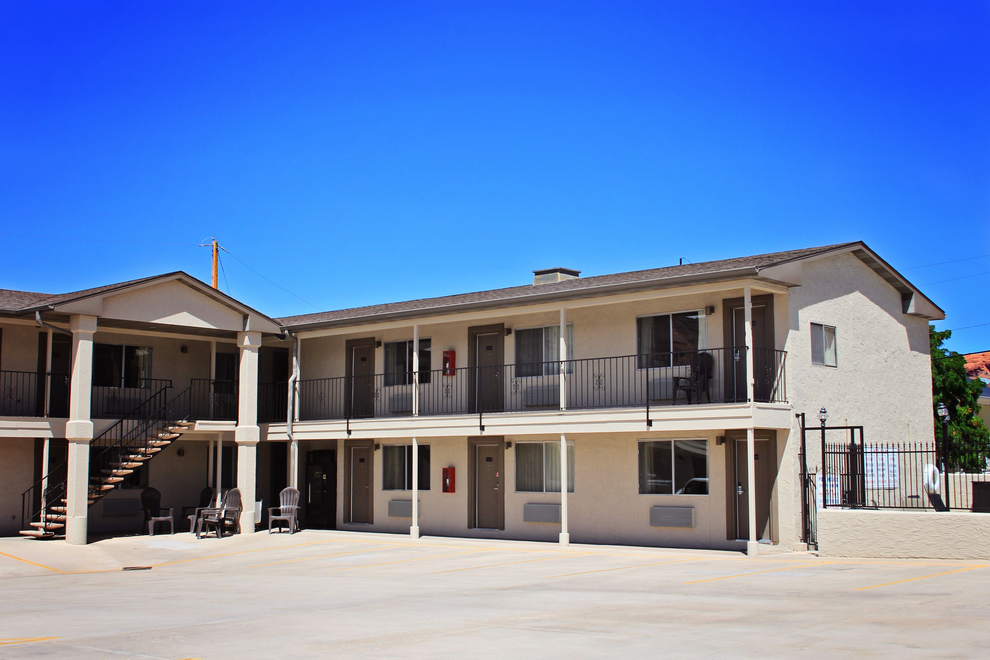 Um motel de dois andares com pátio central, área de estar ao ar livre e hidrante.