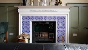 Uma lareira com azulejos azuis e uma alizarola com a inscrição 'ALWAYS LOOK ON THE BRIGHT SIDE OF LIFE'.
