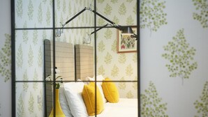 Um quarto com uma cama, um vaso amarelo e uma mesinha.