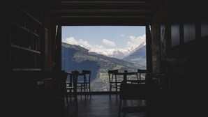 Quarto com uma grande janela com vista para uma paisagem montanhosa.