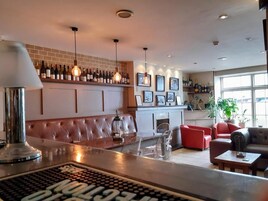 Uma área de bar com um assento de couro, cadeiras transparentes e um espaço para vinhos.