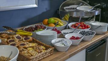 Uma mesa de buffet com diversas frutas, bagas e doces.