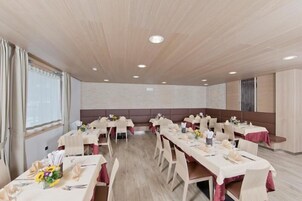 Uma sala de jantar com mesas compridas, cadeiras e teto de madeira.