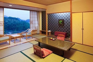Um quarto japonês tradicional com tatames, uma mesa baixa e vista para o exterior.
