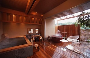 Um deck de madeira com hidromassagem, área de estar e vista para o exterior.