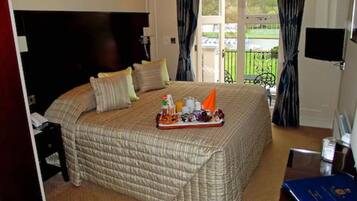 Quarto de hotel com uma cama grande, bandeja de itens de café da manhã, televisão e vista para o exterior.