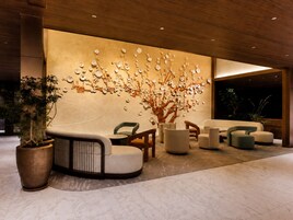 Um lobby moderno com uma grande instalação de arte na parede, arranjos de assentos e um vaso de planta.