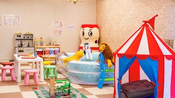 Um espaço de brincadeiras infantil com um escorrega inflável grande, uma tenda e vários brinquedos.