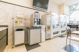 Um saguão de hotel moderno com uma mesa de recepção, uma máquina de café e máquinas de venda automática.