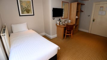 Quarto de hotel com cama, escrivaninha, cadeira, televisão e armário.