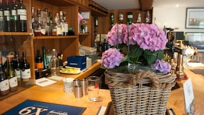 Uma área de bar com uma cesta de vime contendo flores cor-de-rosa, uma taça de martini e um cardápio.