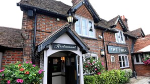 Um edifício de tijolos tradicional com uma placa que diz 'Restaurant' e 'The Swan'.