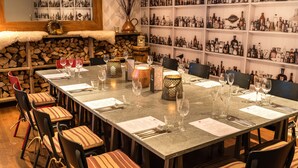 Uma sala de jantar com uma mesa comprida posta para refeição, rodeada por cadeiras com almofadas listradas.