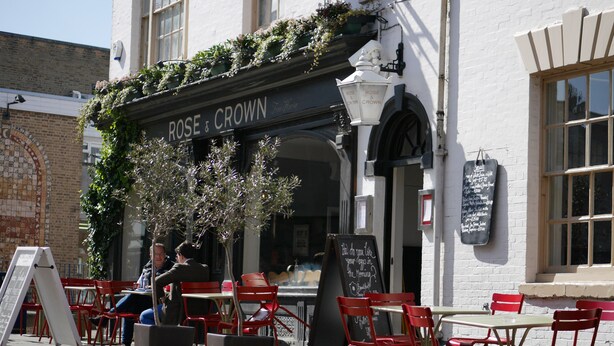 Um café chamado 'Rose & Crown' com mesas ao ar livre e um menu em lousa.