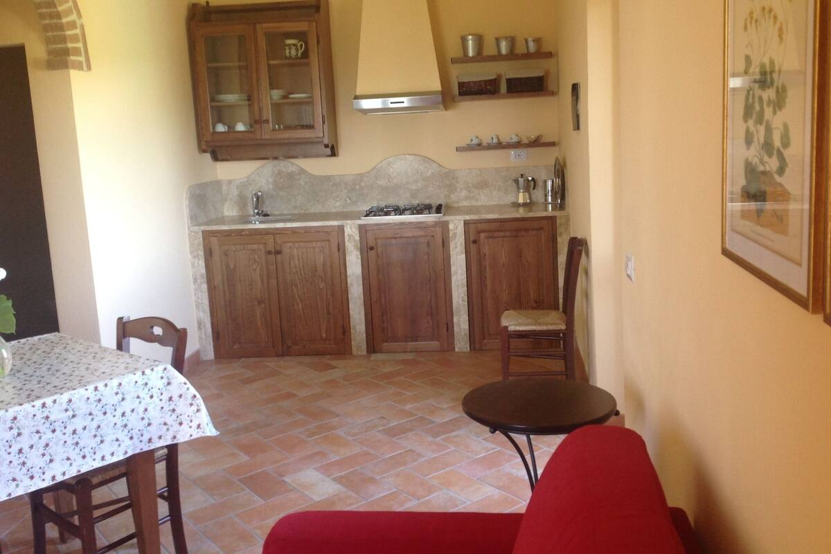 Cozinha compacta com armários de madeira, fogão a gás e um pequeno espaço de jantar com mesa e cadeiras.
