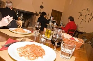 Ambiente de restaurante com mesas, pratos de comida, copos de vinho e garrafas.