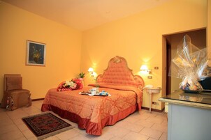 Quarto de hotel com uma cama grande, uma cadeira, uma escrivaninha e um quadro na parede.