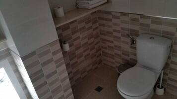 Casa de banho com sanita, bidé e um porta-toalhas.