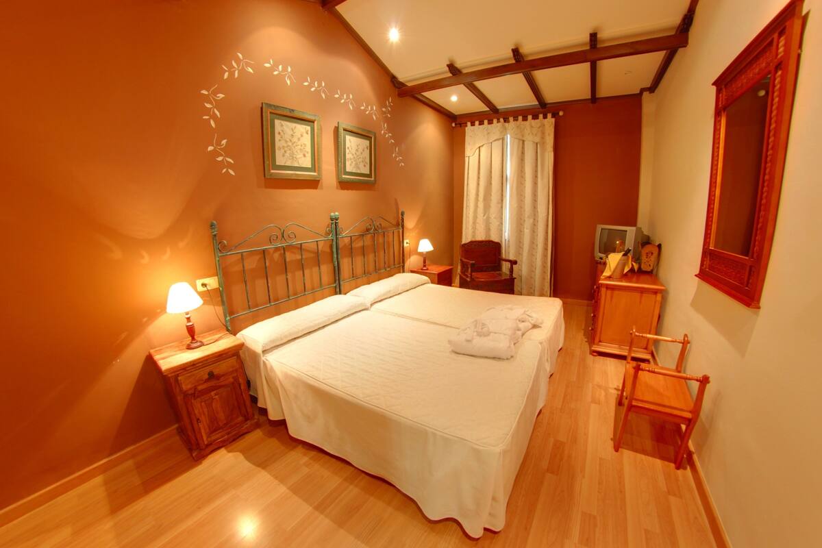 Quarto com cama, mesa de cabeceira, abajur, cadeira e espelho.