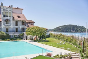 Um hotel com piscina, jardim e vista para o mar.