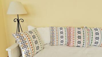 Cama com roupa de cama branca e vários travesseiros com diferentes estampas.