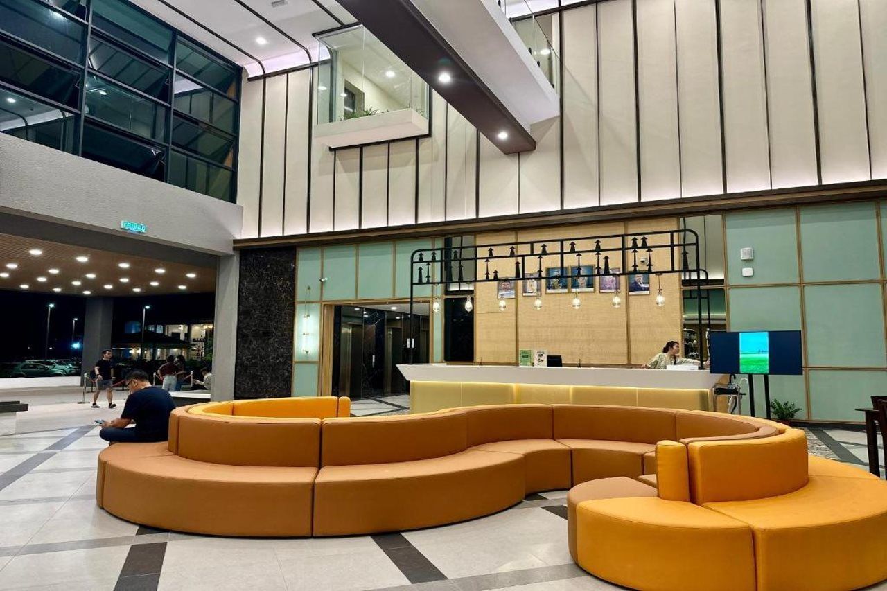 Um lobby moderno com área de estar curvada, balcão de recepção e uma janela grande.