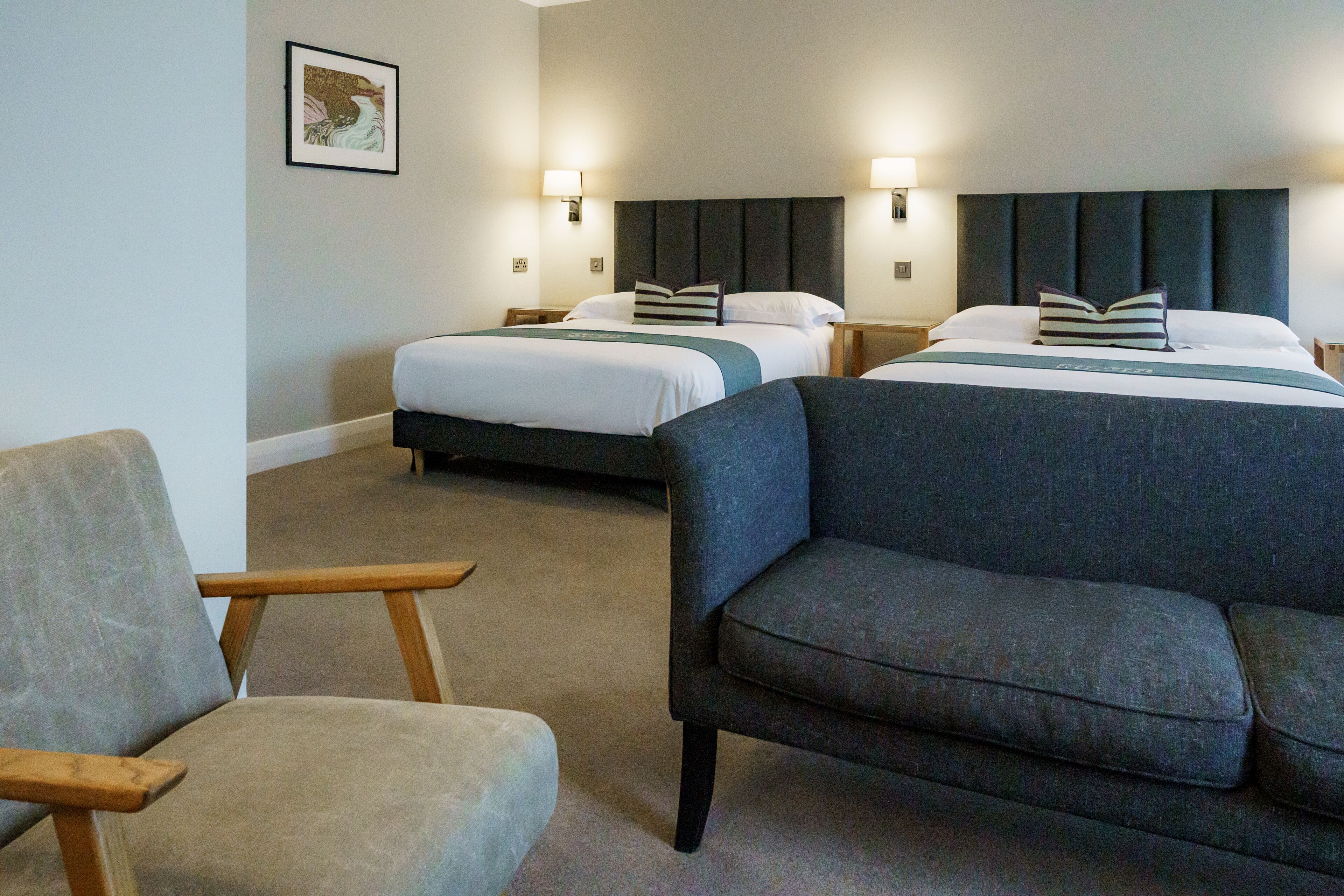 Quarto de hotel com duas camas, um sofá e uma cadeira.