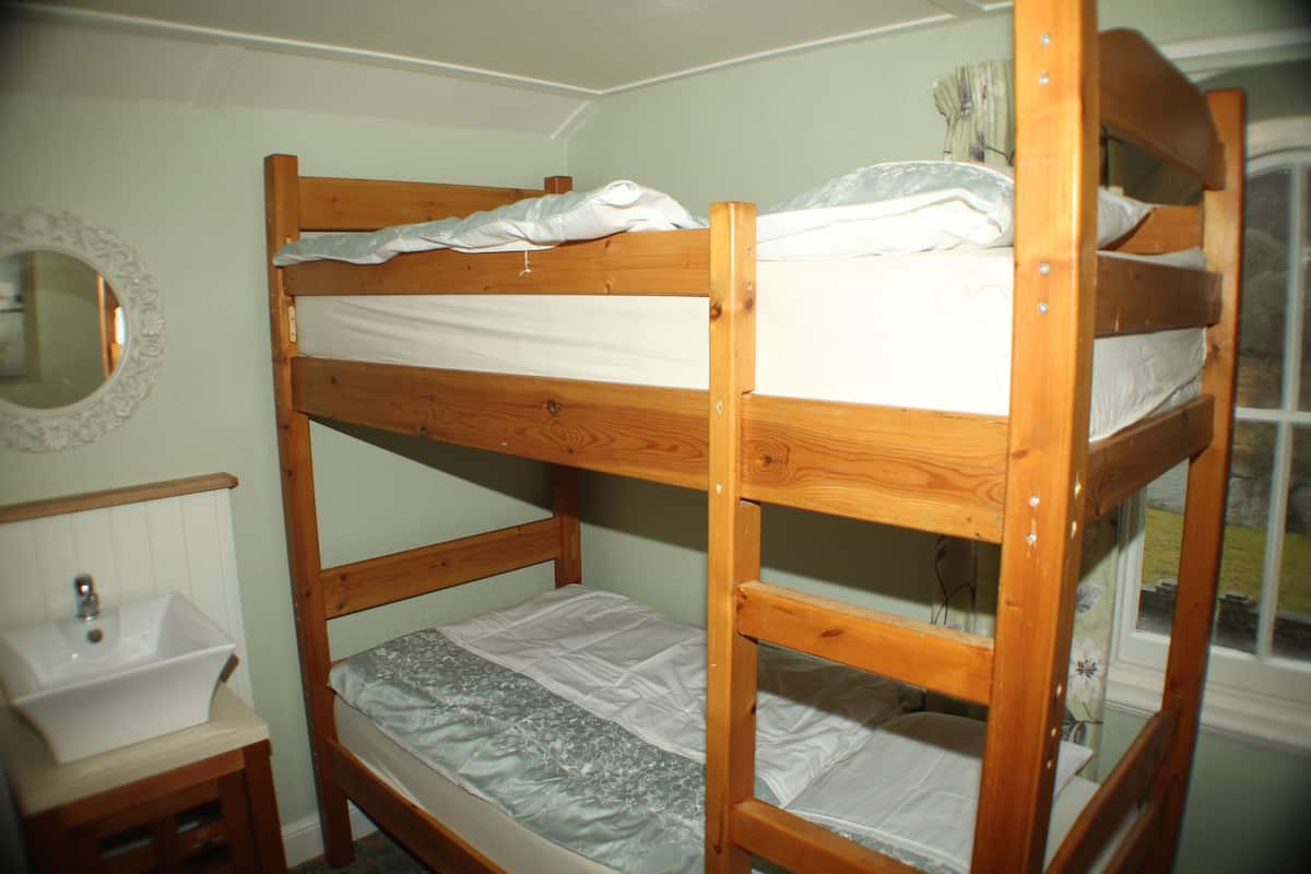 Quarto com beliche de madeira, uma pia pequena e janela.