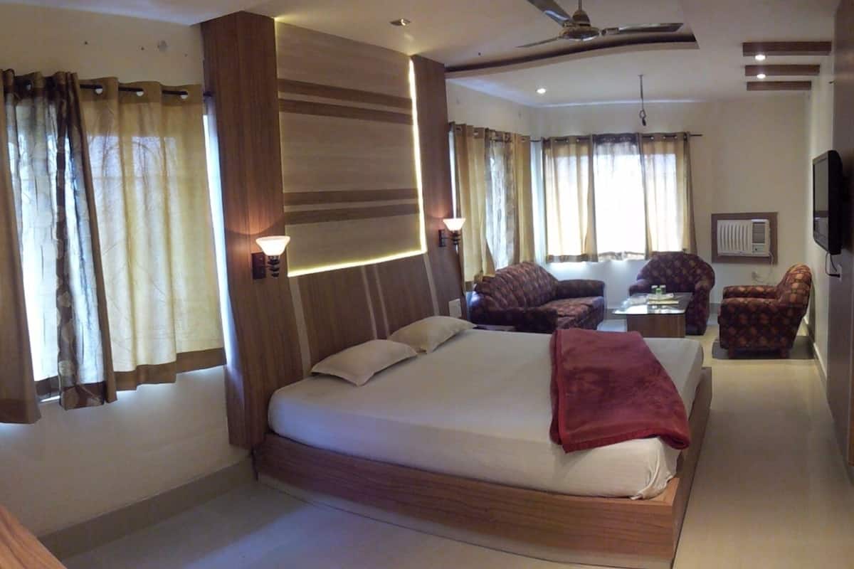 Um quarto espaçoso com uma cama grande, uma área de estar com sofás e uma televisão.