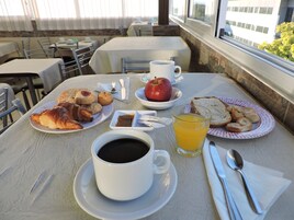 Uma mesa de café da manhã com croissants, um copo de suco de laranja, uma xícara de café e uma fatia de torrada.