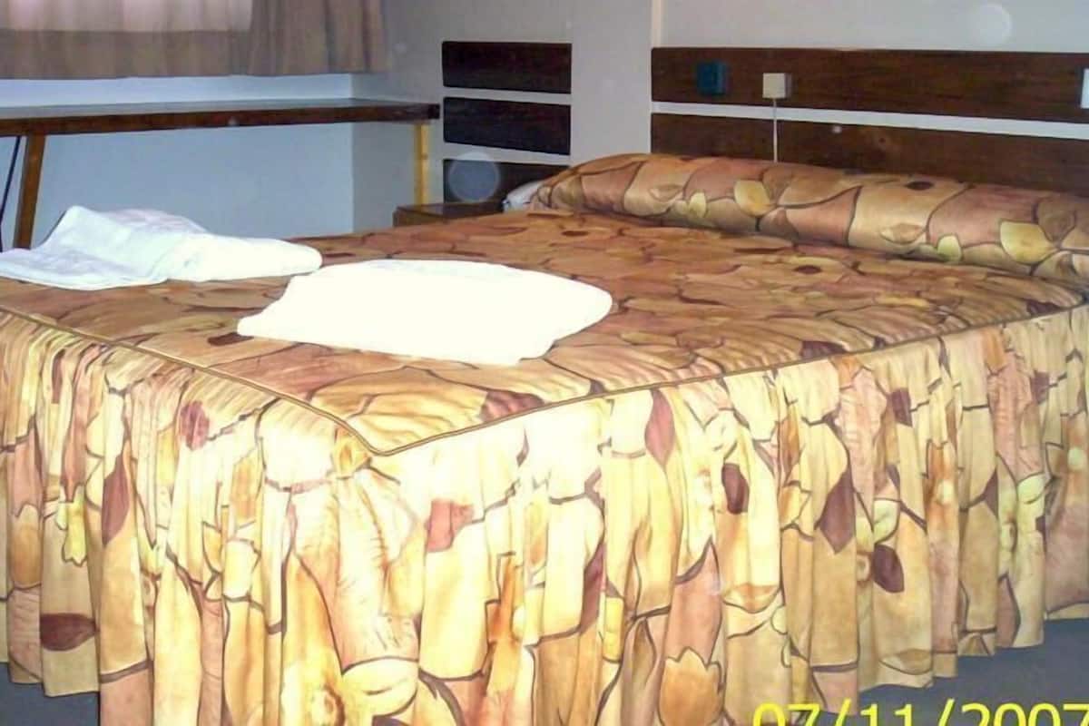 Uma cama com colcha estampada em flor e cabeceira de madeira.