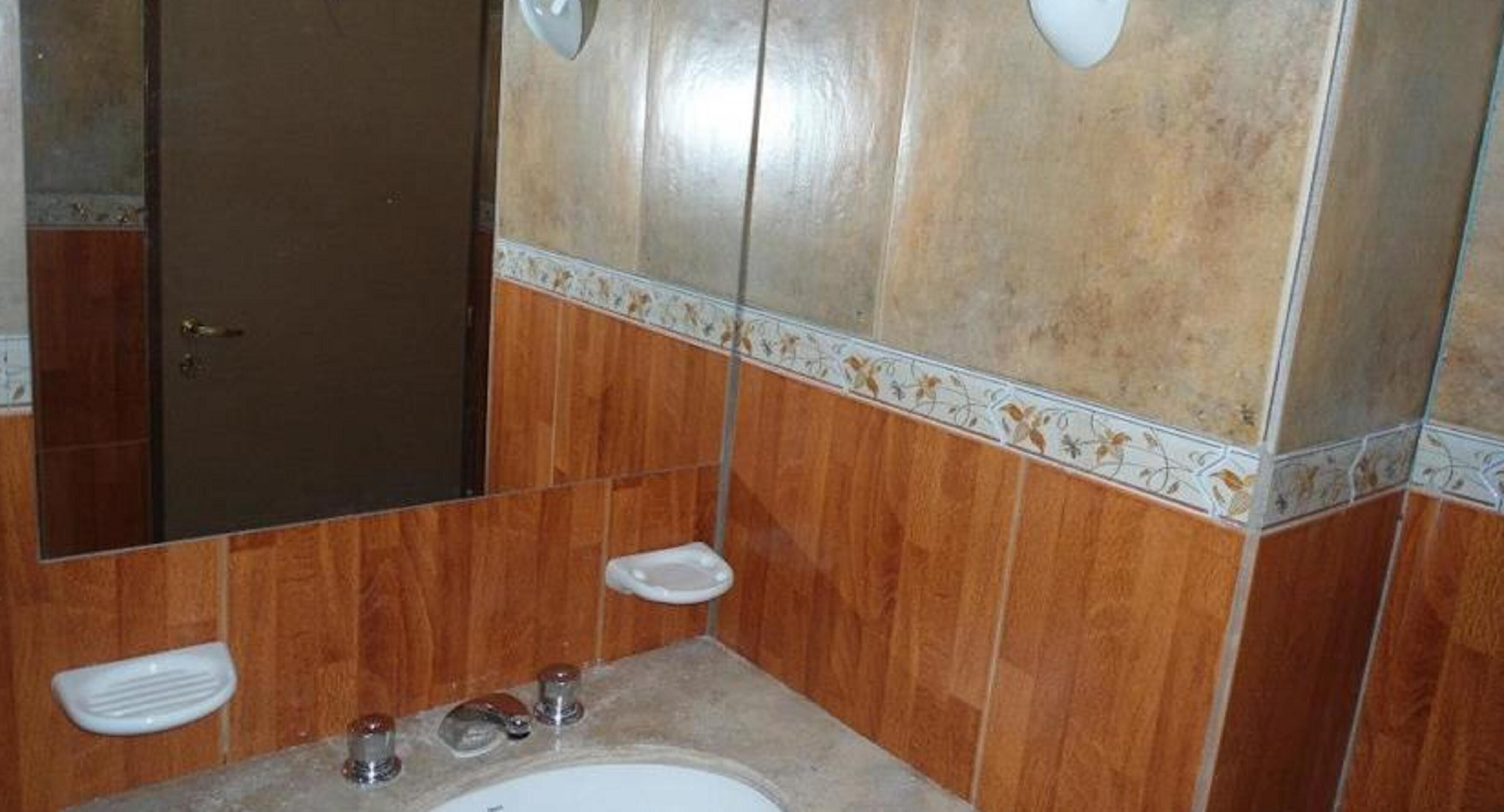 Casa de banho com lavatório, espelho e duas pequenas prateleiras.