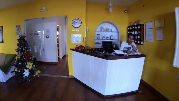 Uma área de recep ção com balcão branco, uma árvore de Natal e uma geladeira ao fundo.