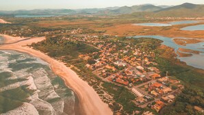 Vista aérea de uma cidade costeira com praia, áreas residenciais e um rio.