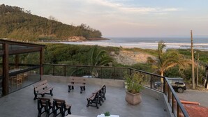 Terraço com área de estar ao ar livre, com vista para uma praia e oceano.