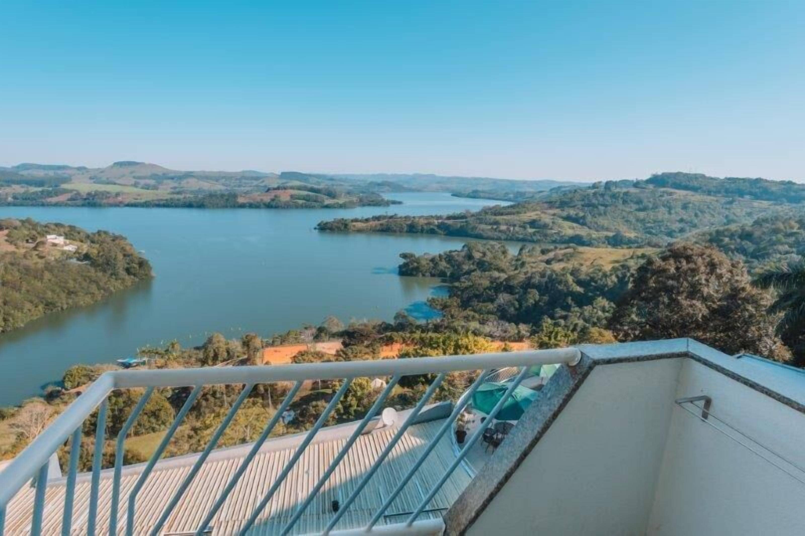 Uma varanda com vista para um lago rodeado por colinas.