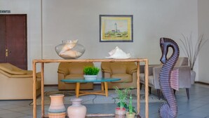 Sala de estar com sofá, mesa de centro, objetos decorativos e um quadro na parede.