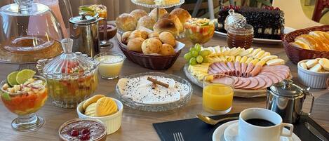 Um buffet de café da manhã com diversas opções de alimentos e bebidas.